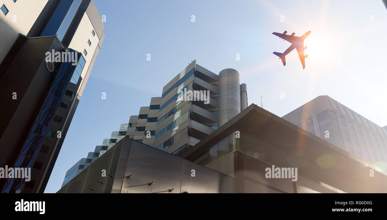 Bottom angle view of airplane in sky over city buildings Stock Photo ...