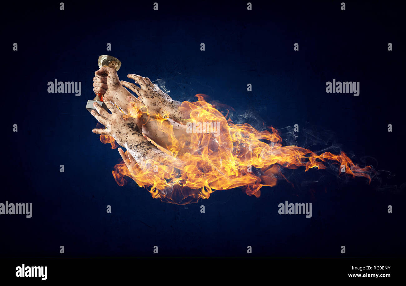 Man arm holding burning trophy cup on dark background Stock Photo - Alamy