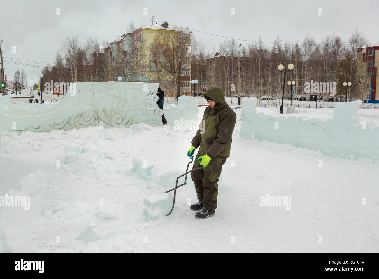 The worker pulls the ice block around the ice camp assembly site with ...