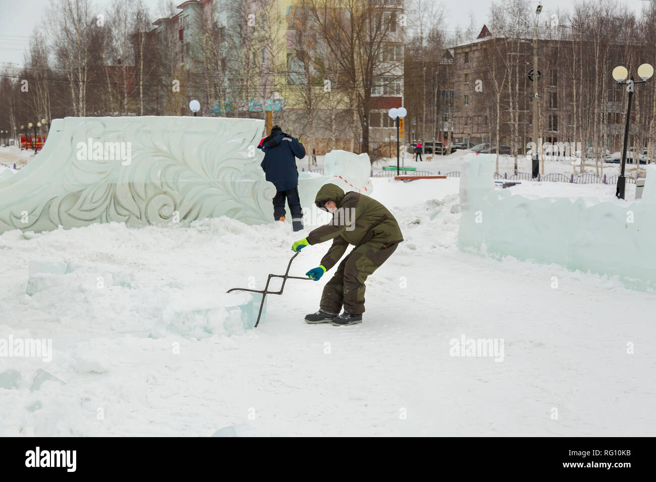 The worker pulls the ice block around the ice camp assembly site with ...