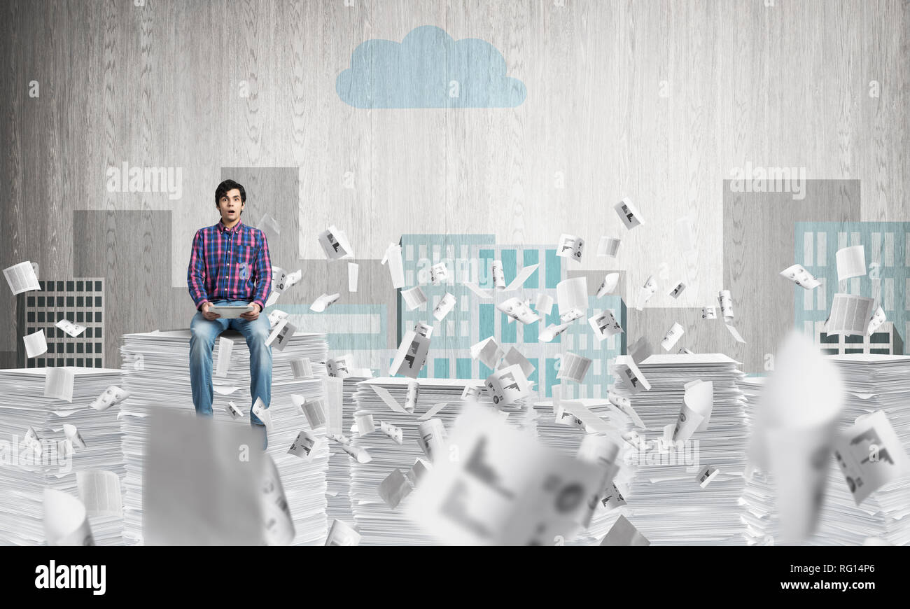 Young man sitting on pile of paper documents Stock Photo - Alamy