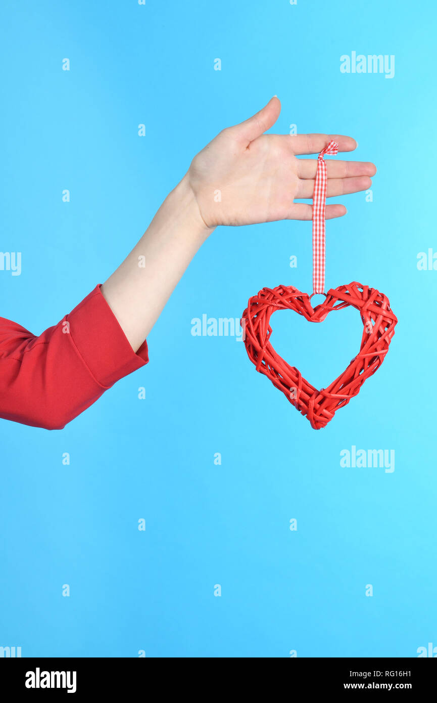 Woman hand holding symbol heart in hand isolated over blue background ...