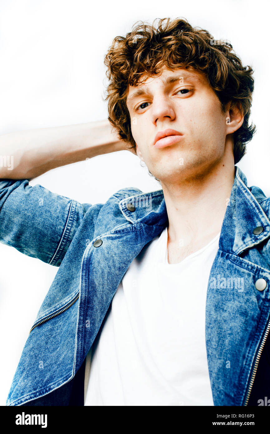 Portrait of a smart serious young man standing against white background ...