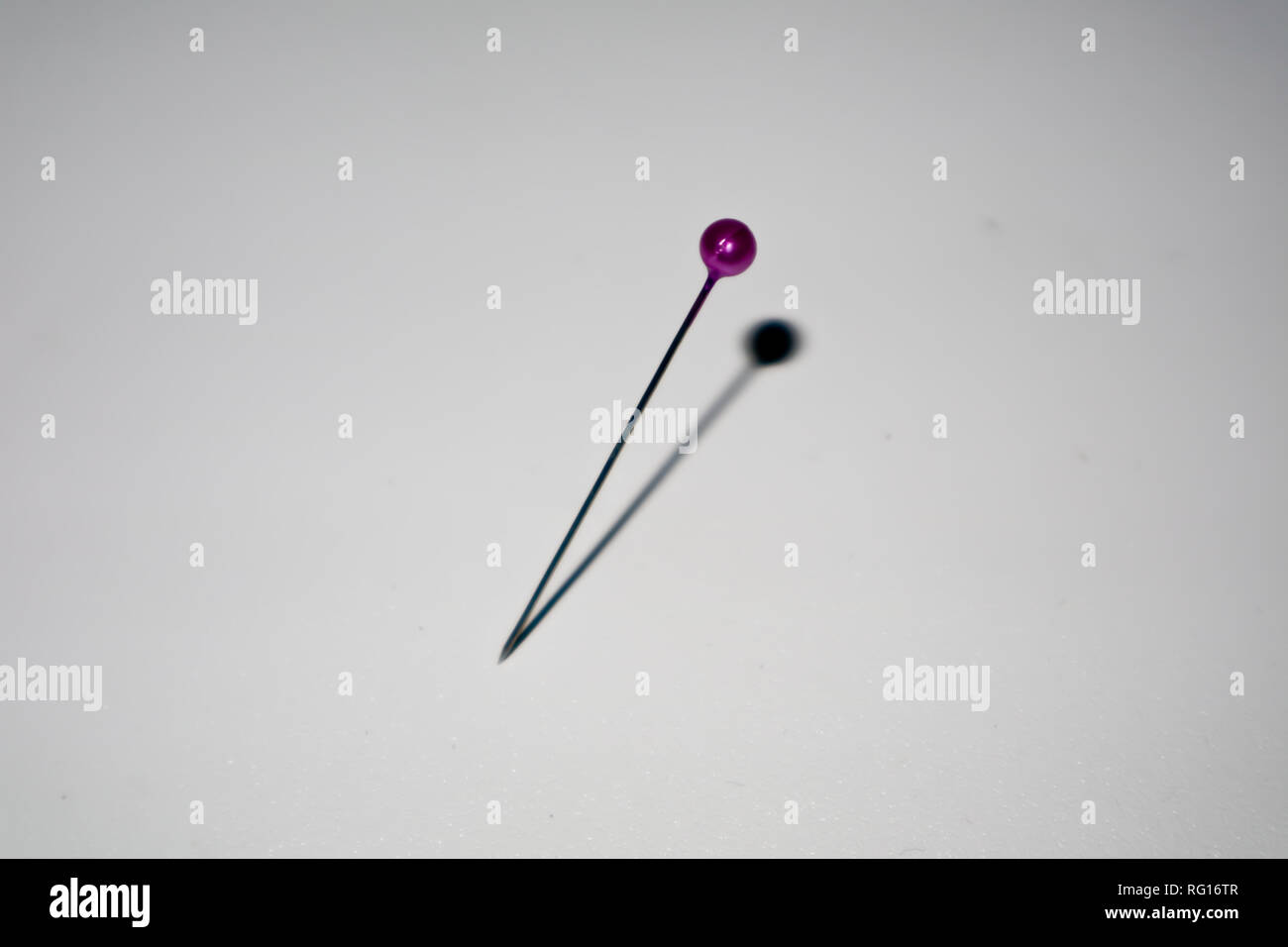 purple pin sticked in white background Stock Photo - Alamy