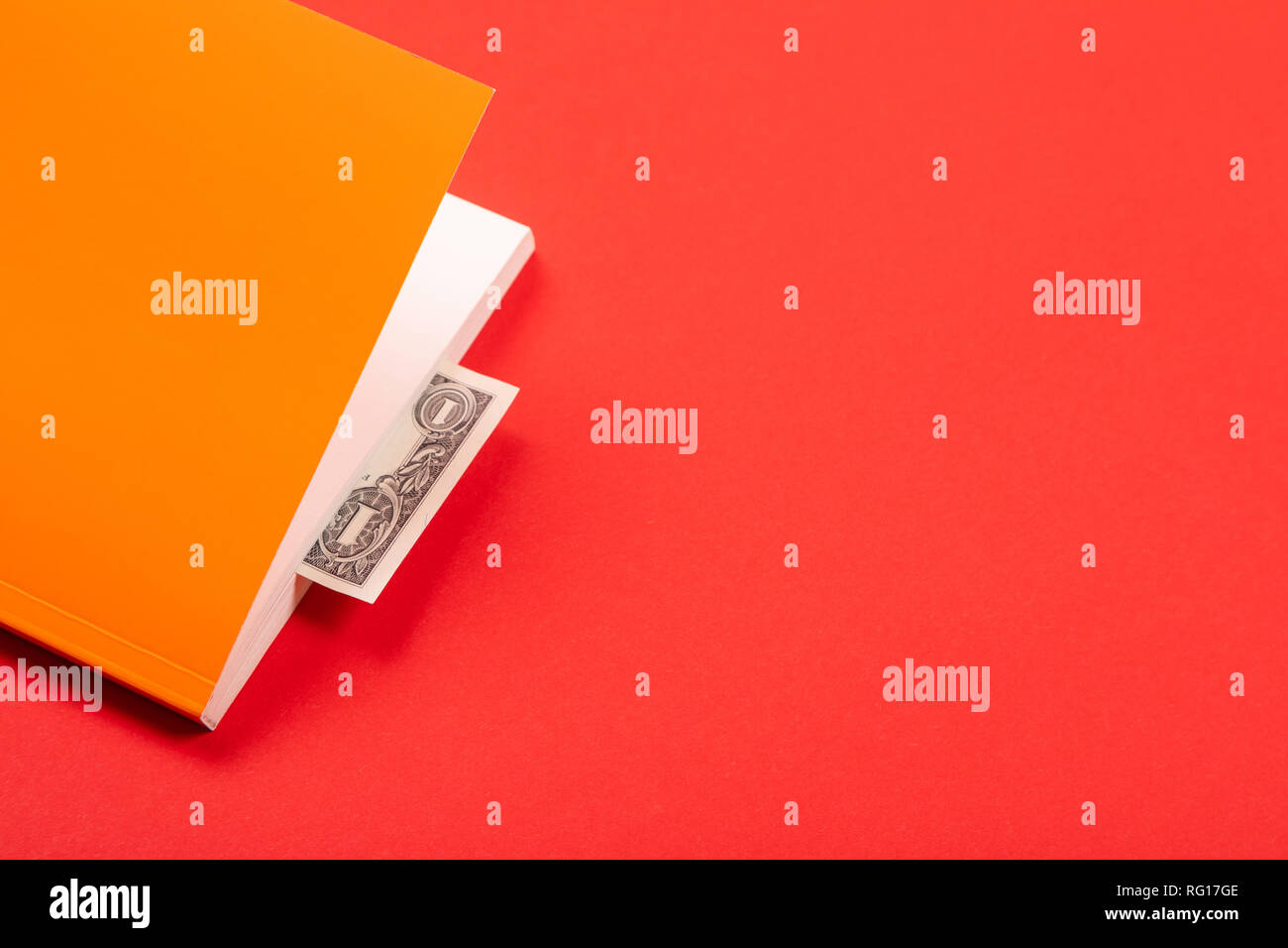 dollar as a bookmark in the orange book isolated on red background ...