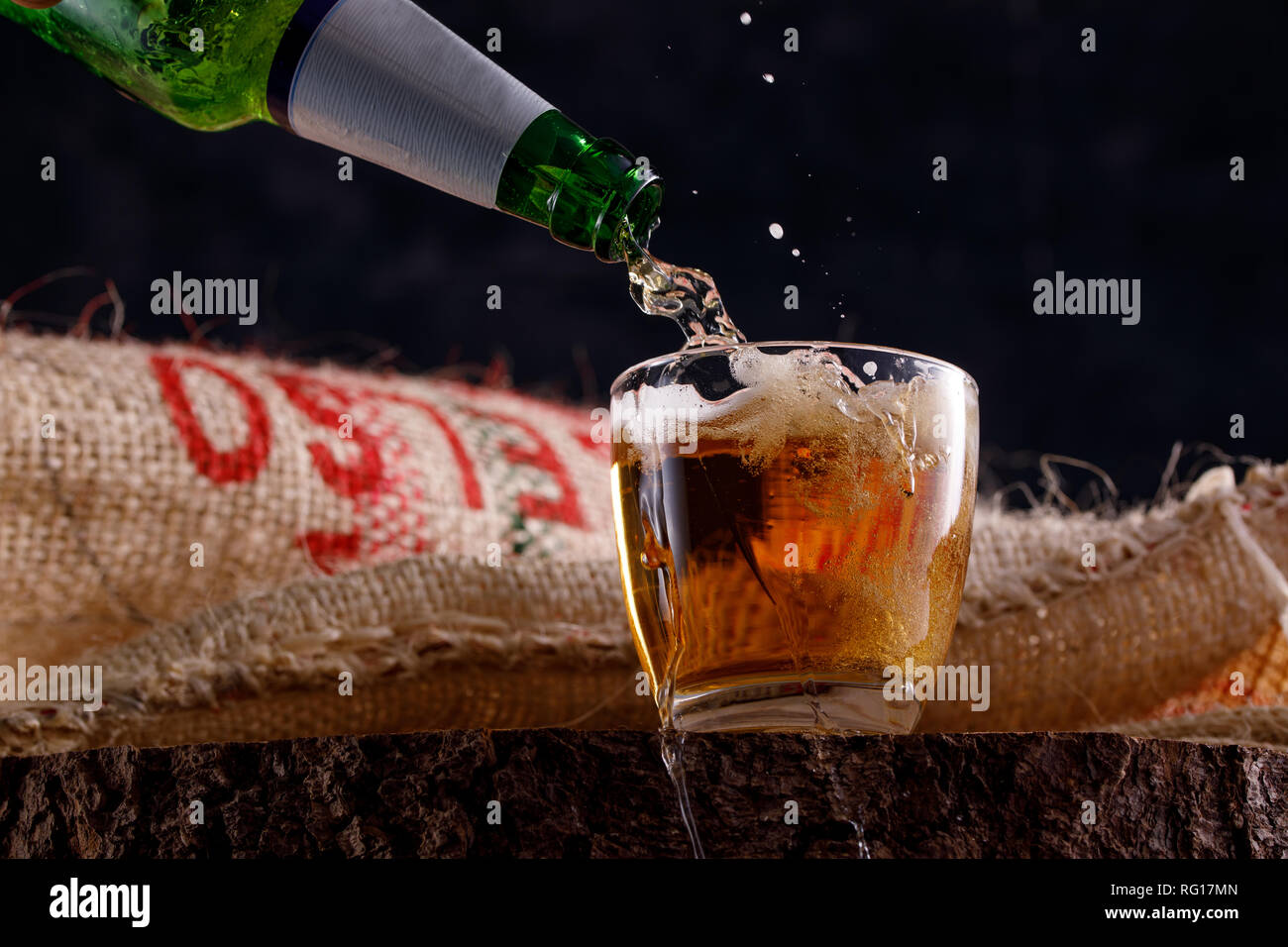 Light beer pours from a bottle into a glass goblet against the ...