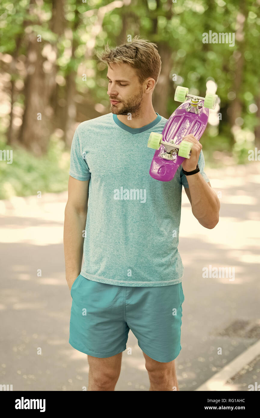 Still childish. Man calm face carries penny board park nature ...