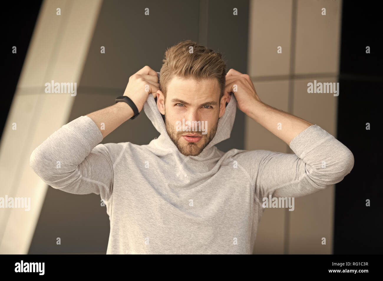 Guy bearded and attractive puts on hood. Man with bristle on serious ...