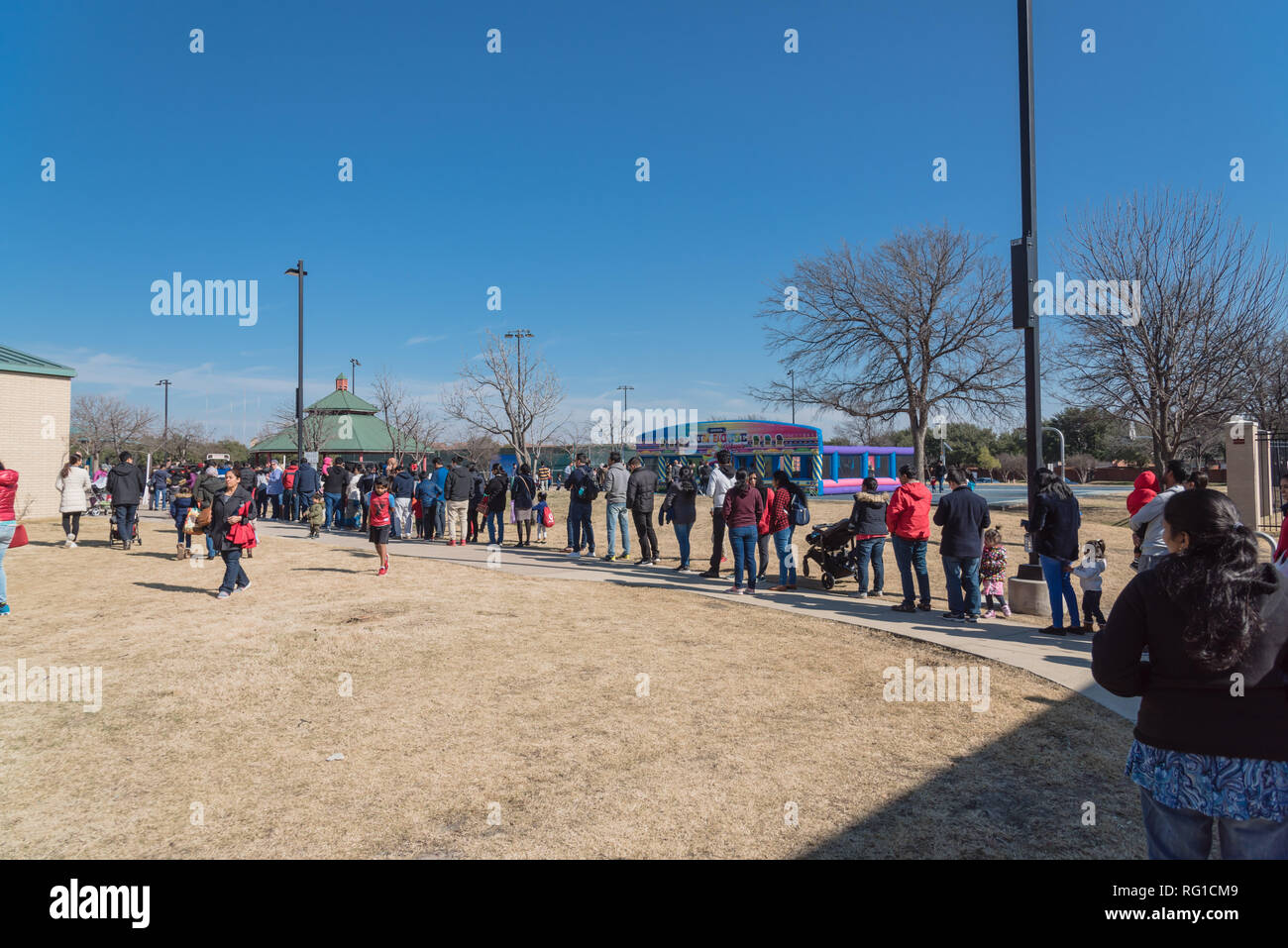 Diverse group of people queue in line to attend outdoor winter festival ...