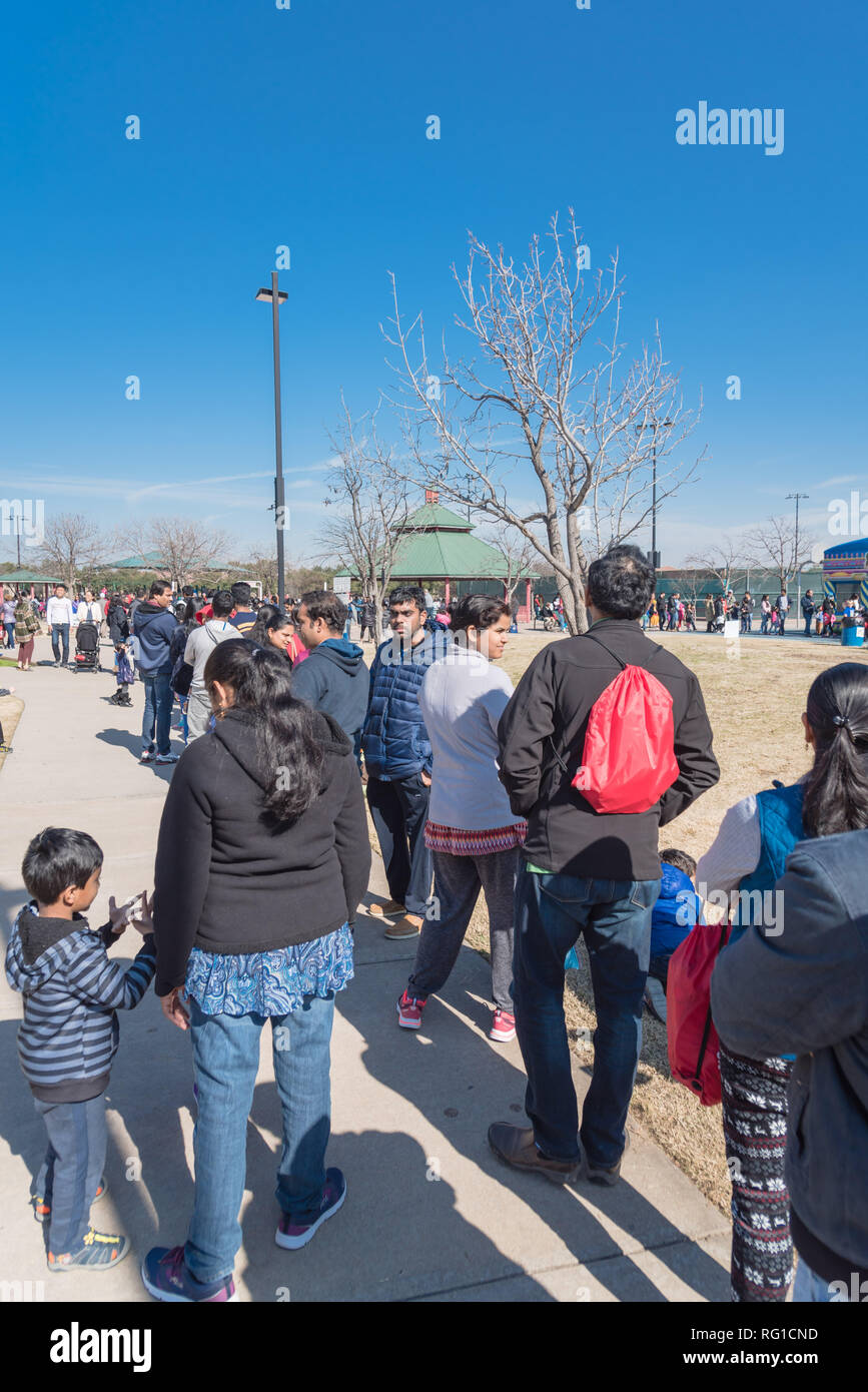 Diverse group of people queue in line to attend outdoor winter festival ...