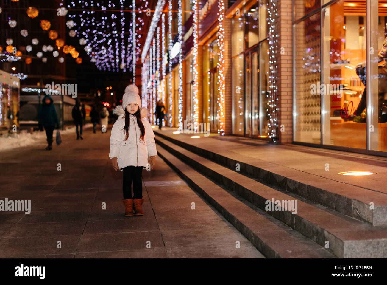 Cute scared lost little girl in a big city in the evening in winter ...