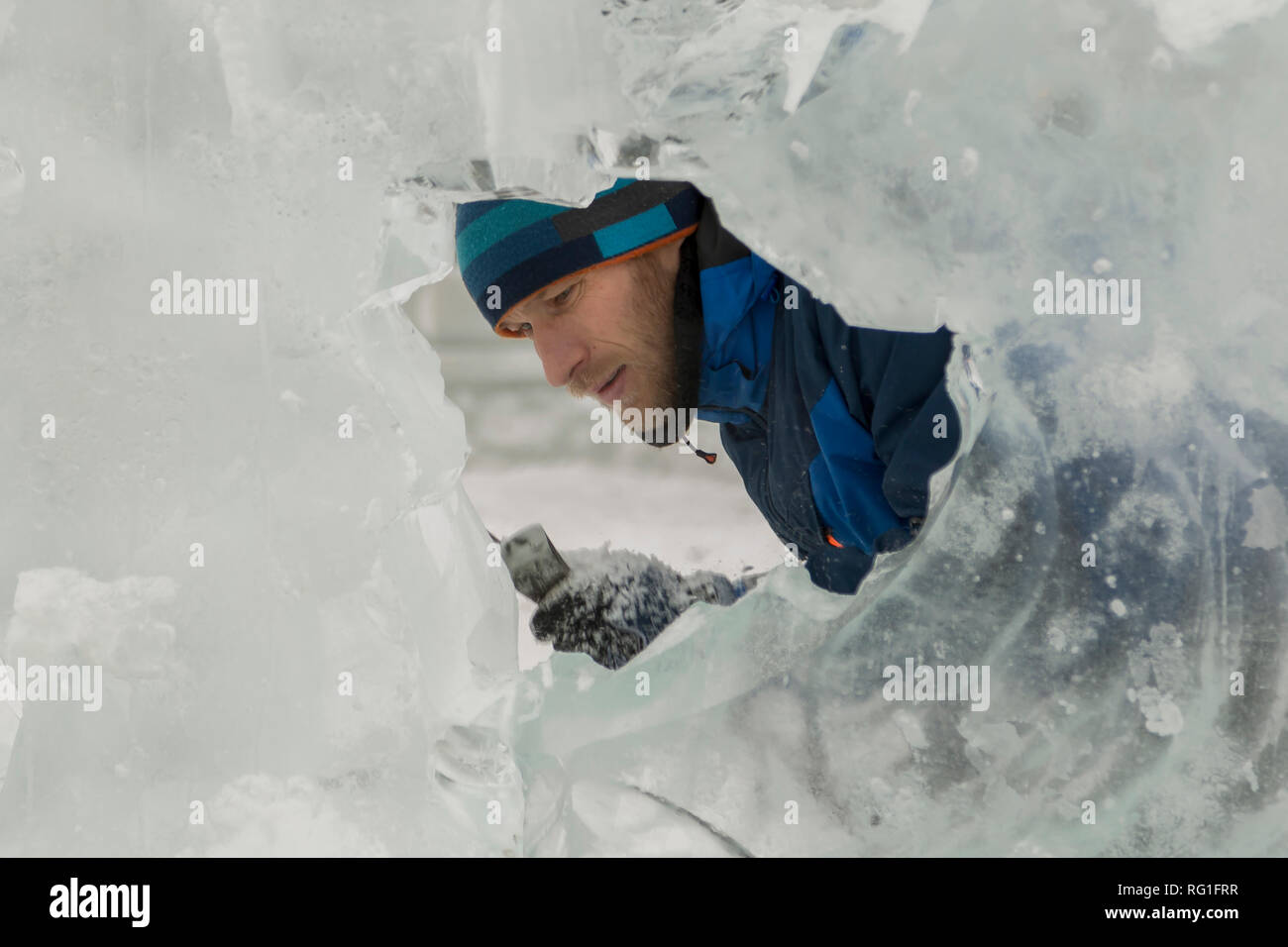 The sculptor cuts an ice figure out of ice with a chisel for Christmas ...