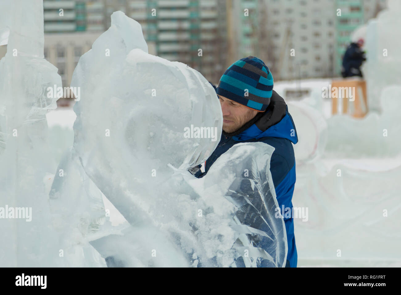 The sculptor cuts an ice figure out of ice with a chisel for Christmas ...