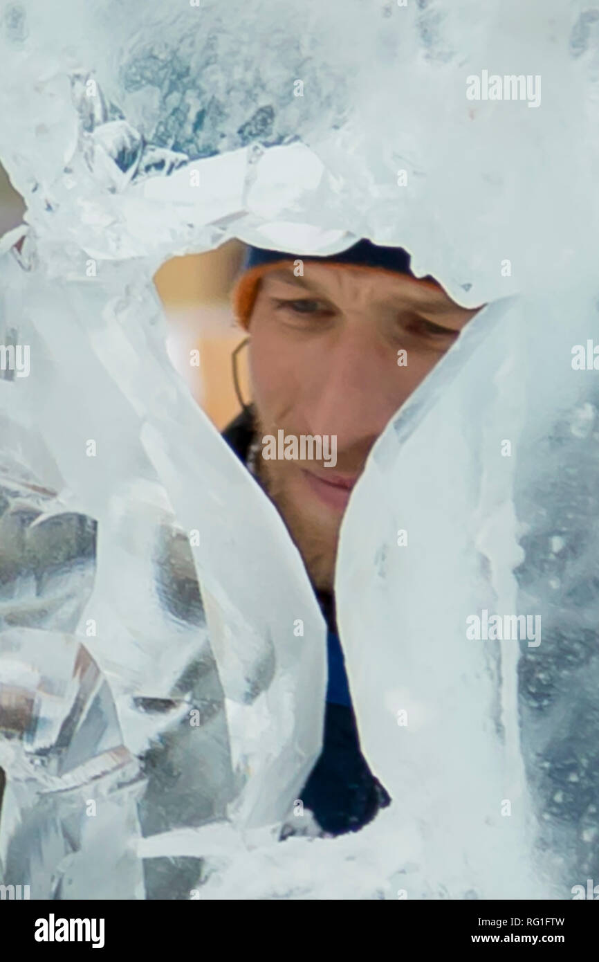 The sculptor cuts an ice figure out of ice with a chisel for Christmas ...