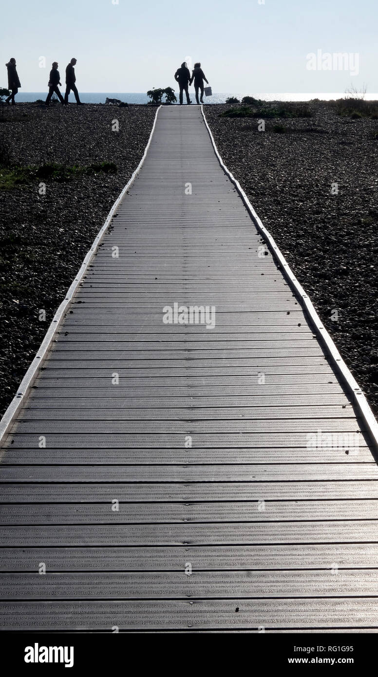 five silhouetted unrecognisable people walking across the end of a long ...