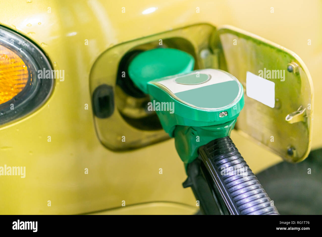 Yellow, gold car at a gas station being filled with fuel Stock Photo ...