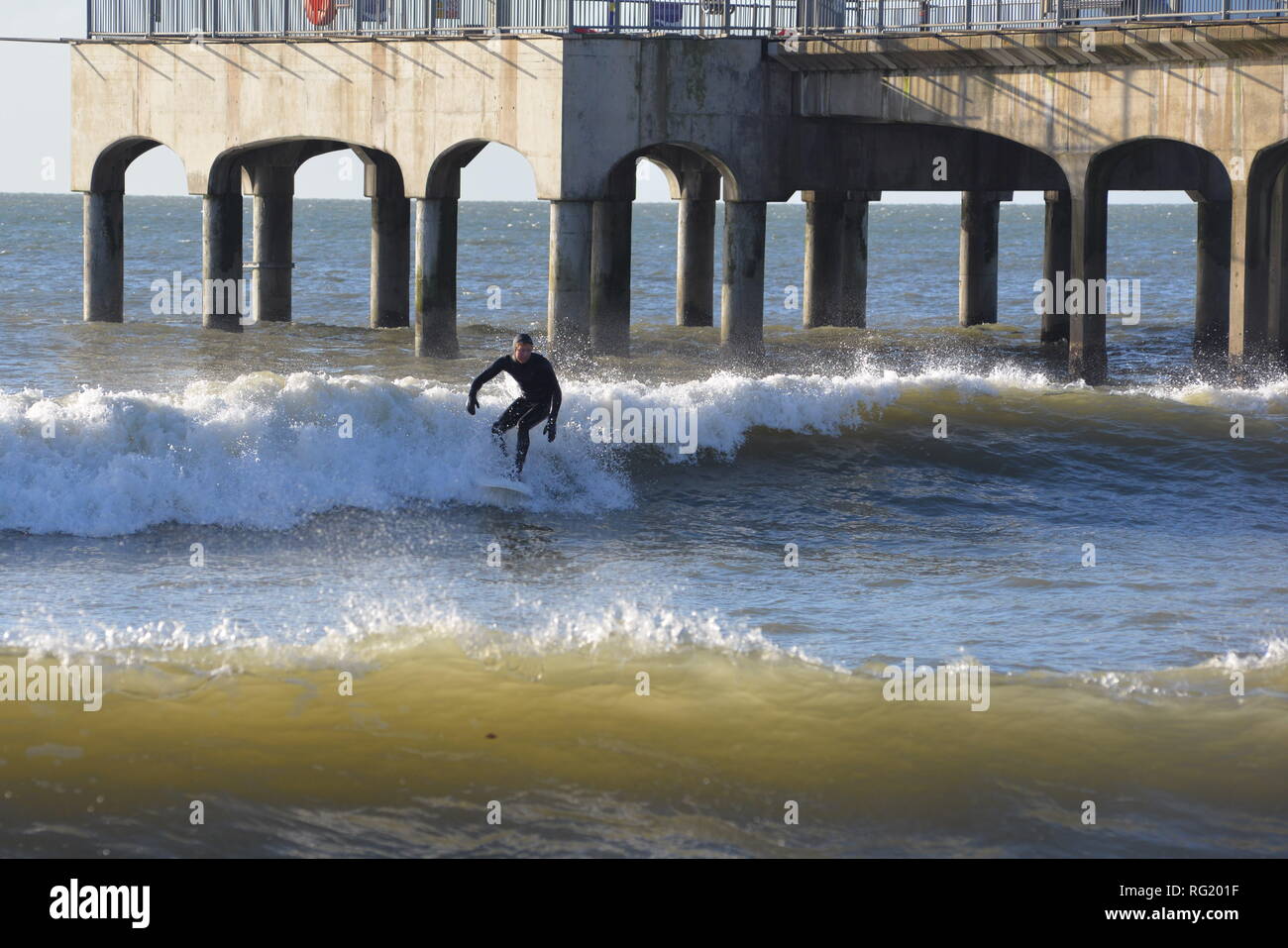 Surfer riding a wave at Boscombe, Bournemouth, Dorset, UK in January ...