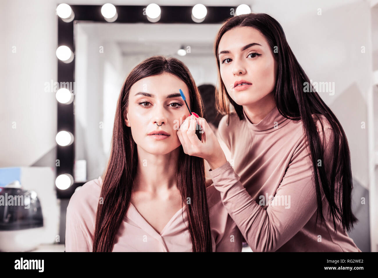 Nice young woman correcting the shape of eyebrows Stock Photo - Alamy