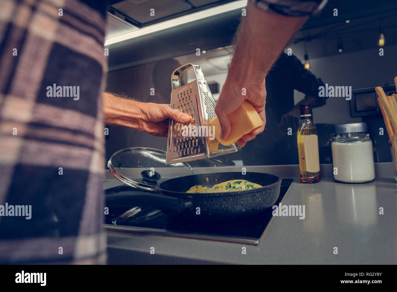 Tall man in a checkered shirt grating cheese on the omelet Stock Photo ...