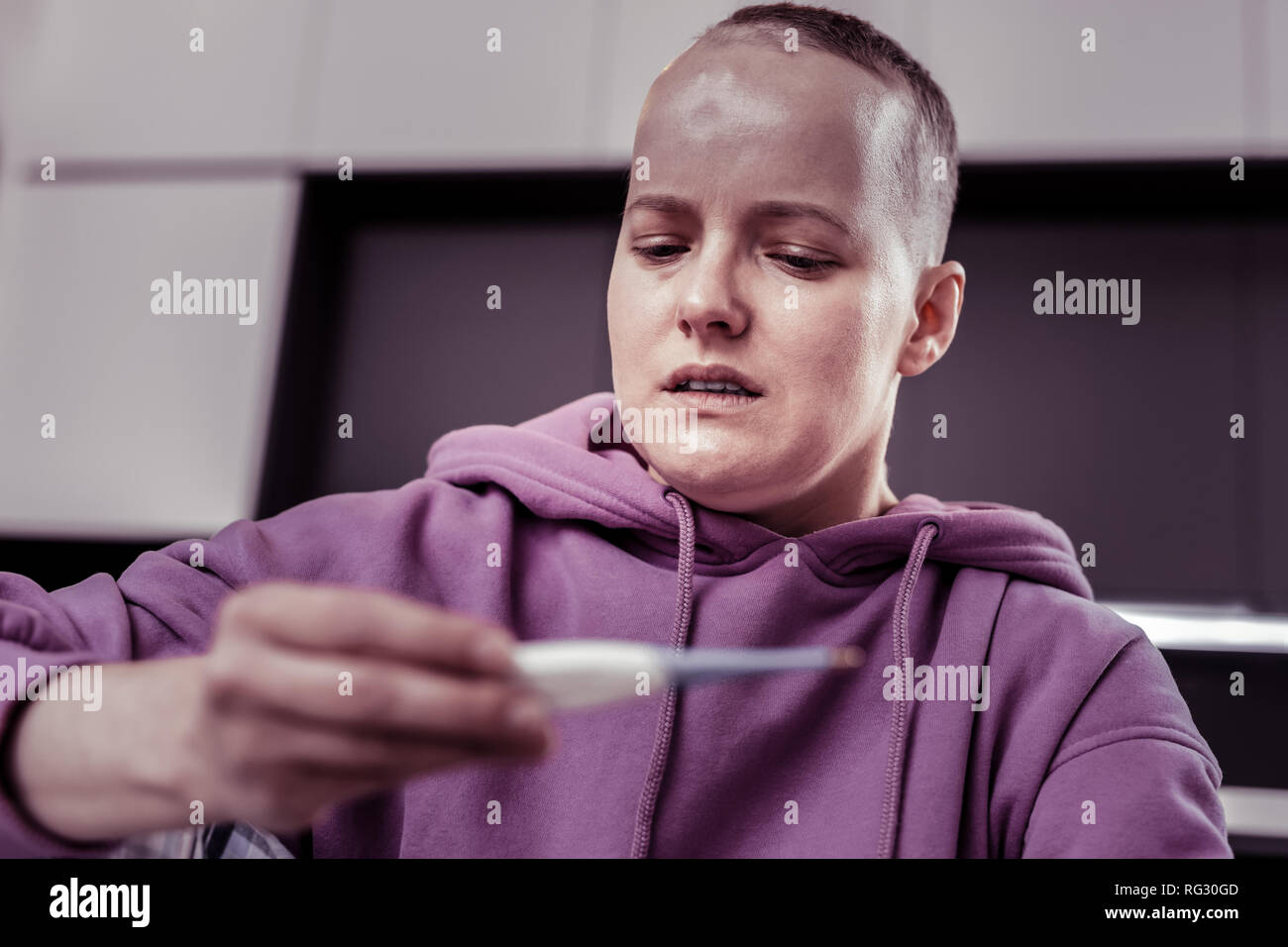 Serious ill woman looking at electronic thermometer Stock Photo - Alamy