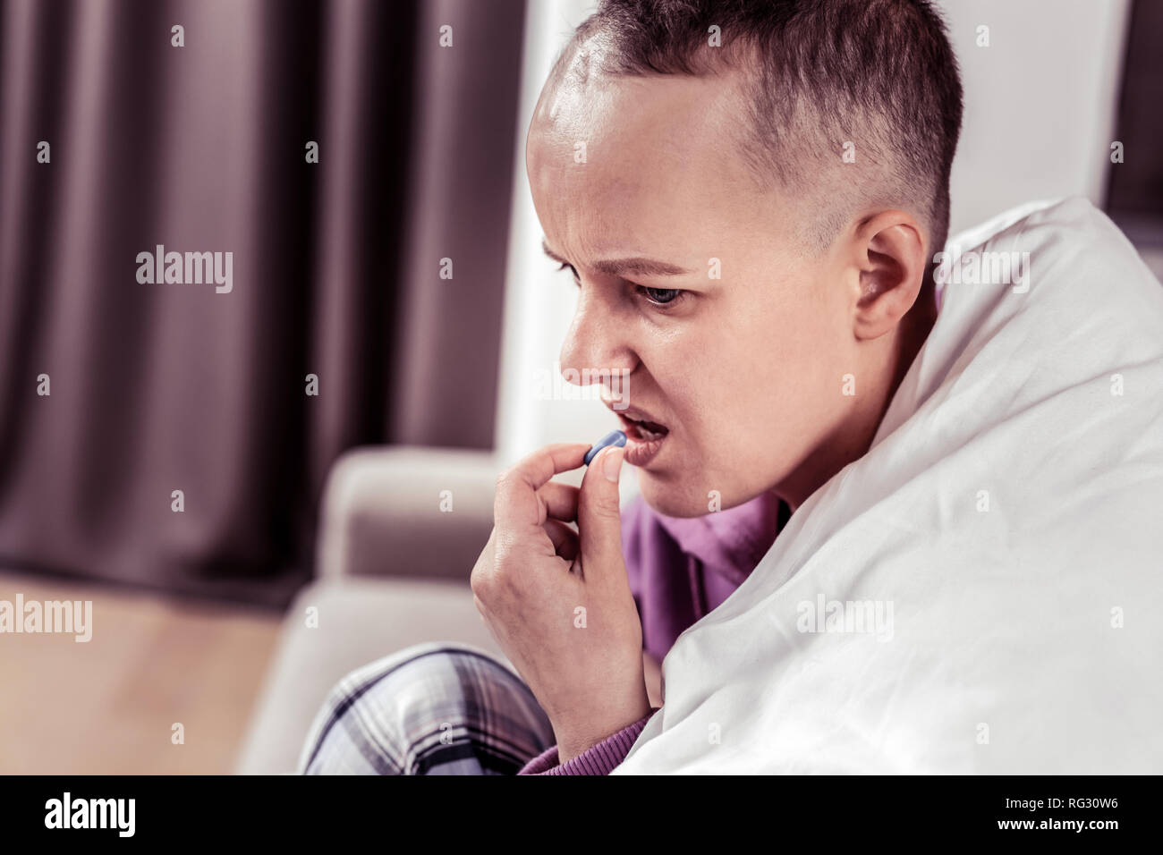 Low spirited young female pitting tablet in mouth Stock Photo - Alamy