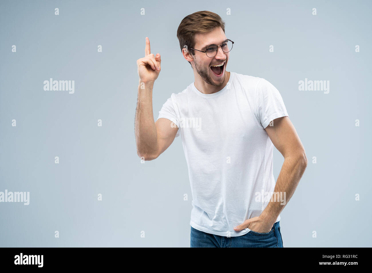 Portrait of a happy young man pointing fingers up at copy space ...