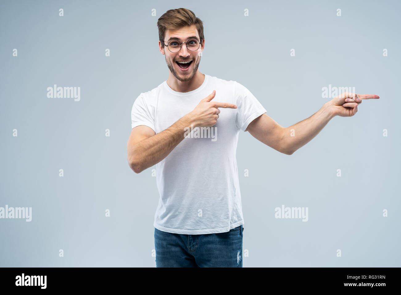 Portrait of a joyful young man pointing fingers away at copy space on ...