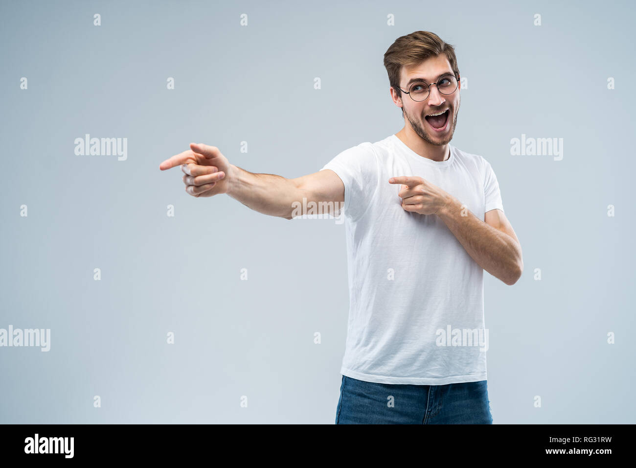 Portrait of a joyful young man pointing fingers away at copy space on ...