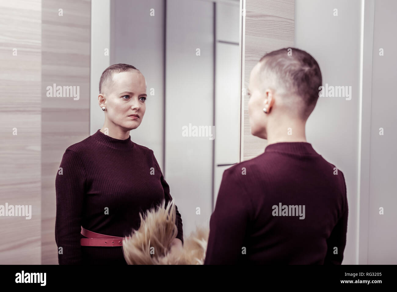 Gloomy bold girl looking at her reflection Stock Photo - Alamy