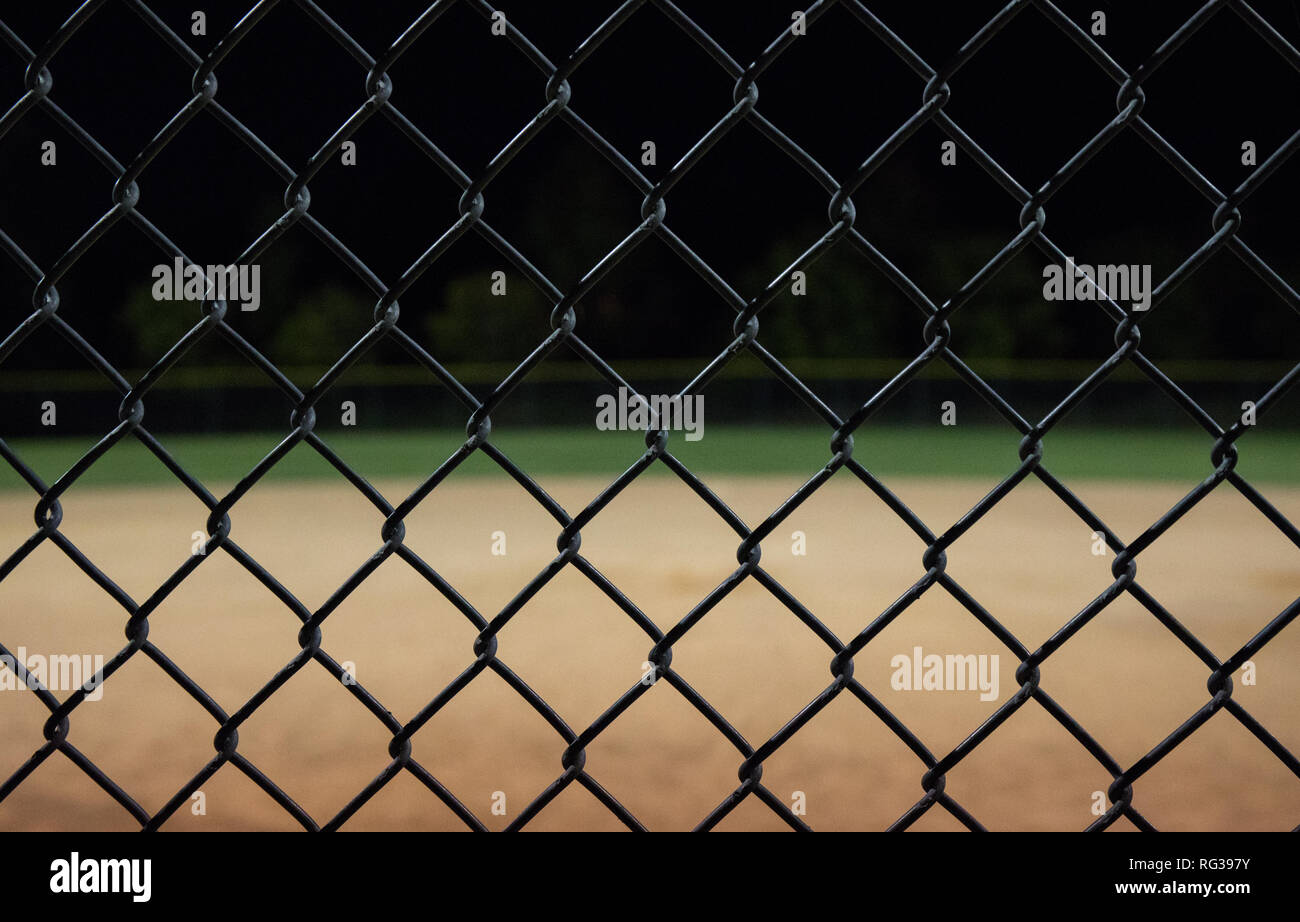 Close up photo of a baseball field fence looking through it to an empty ...