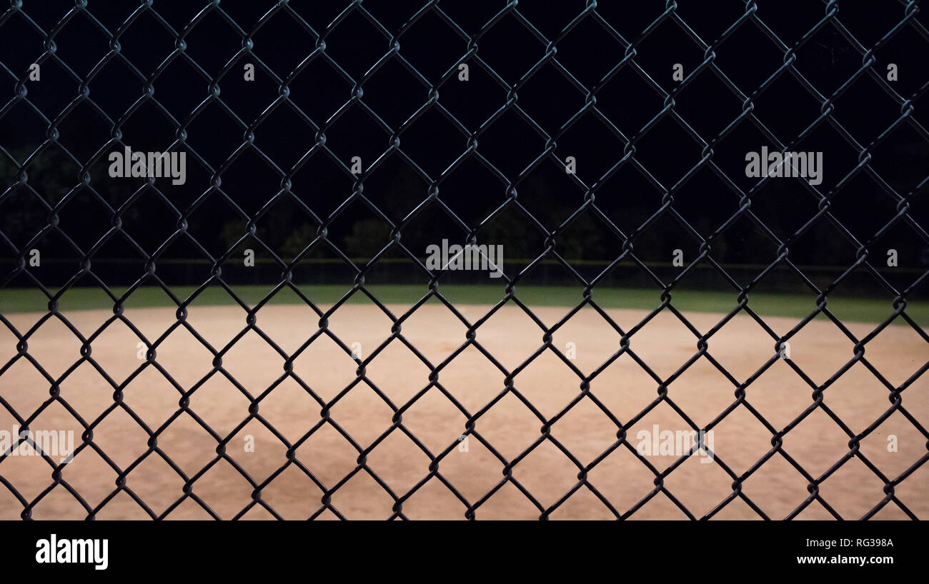 Close up photo of a baseball field fence looking through it to an empty ...