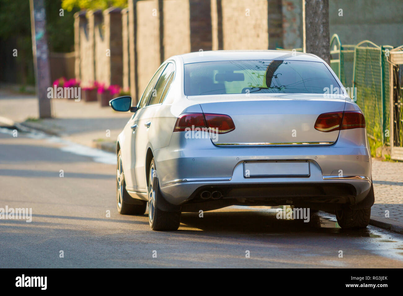 Close-up back view of new shiny expensive silver car moving along city ...