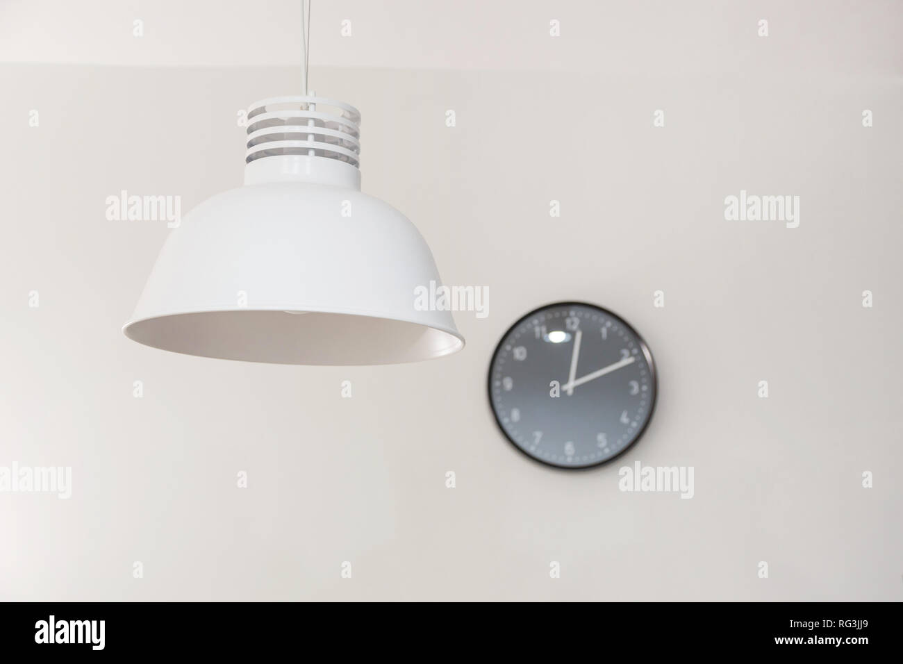 Stylish lamp and clock on wall Stock Photo - Alamy