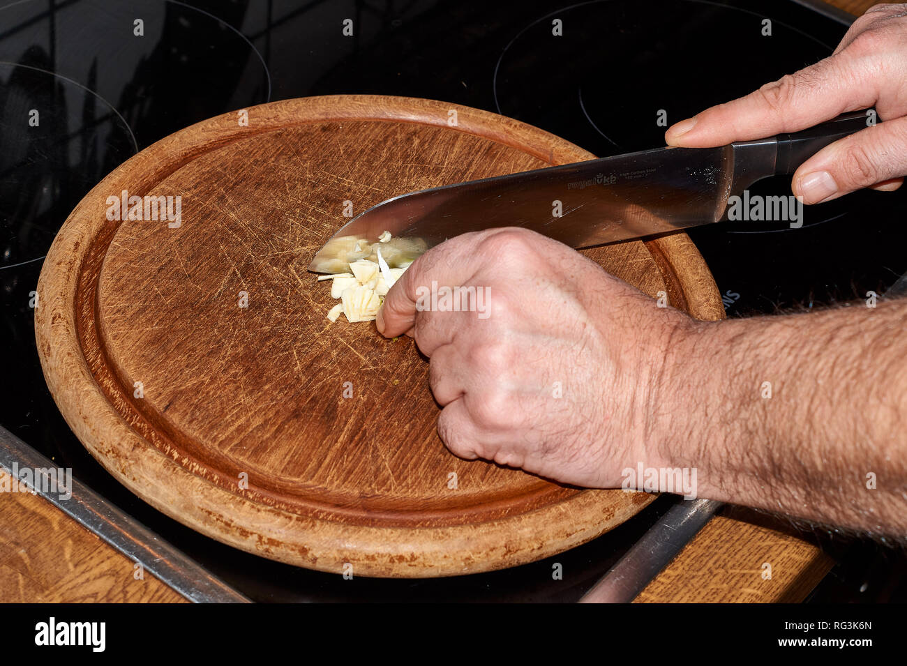 Chef slicing garlic Allium sativum on the cutting board with a knife ...