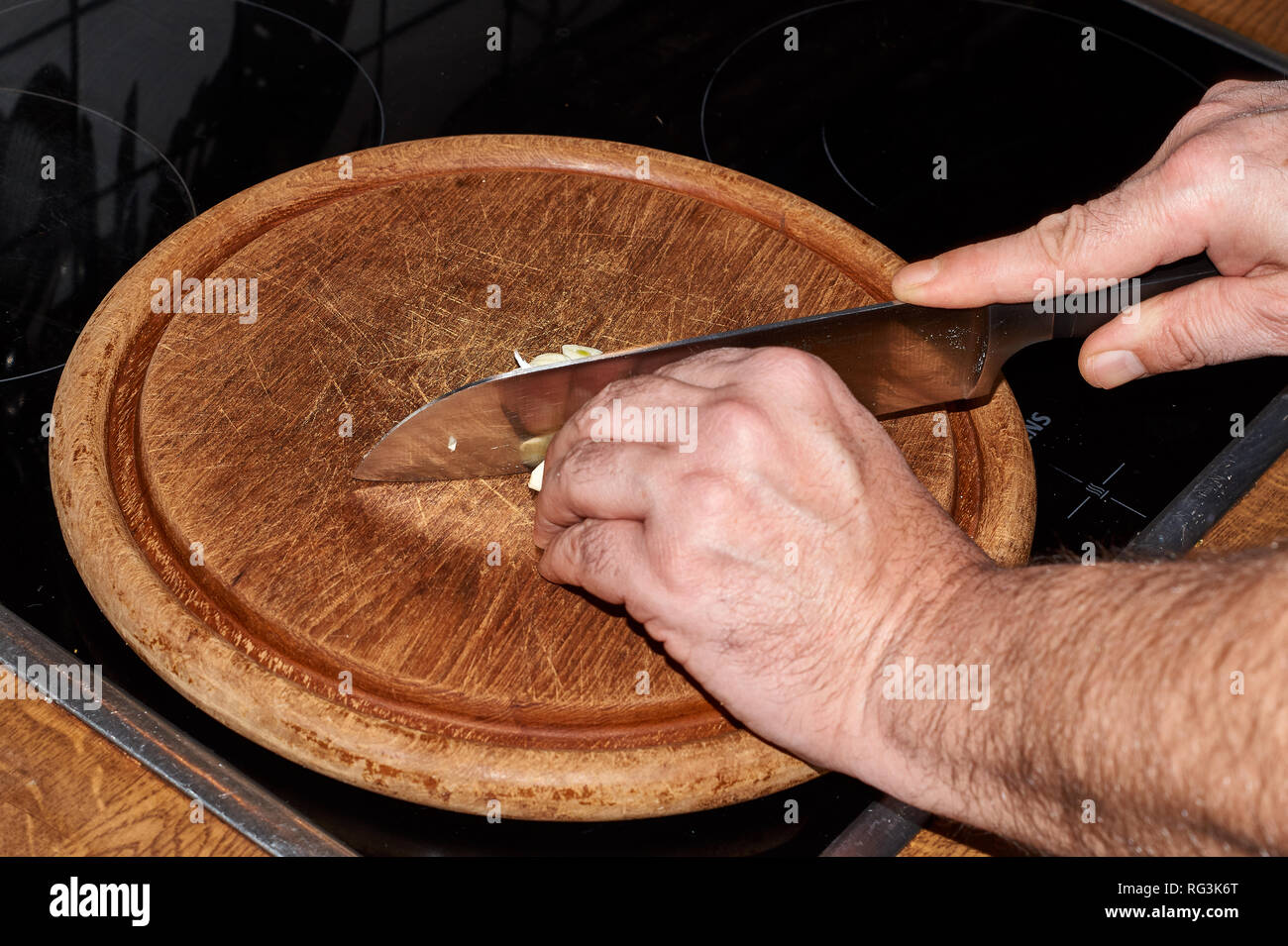 Chef slicing garlic Allium sativum on the cutting board with a knife ...