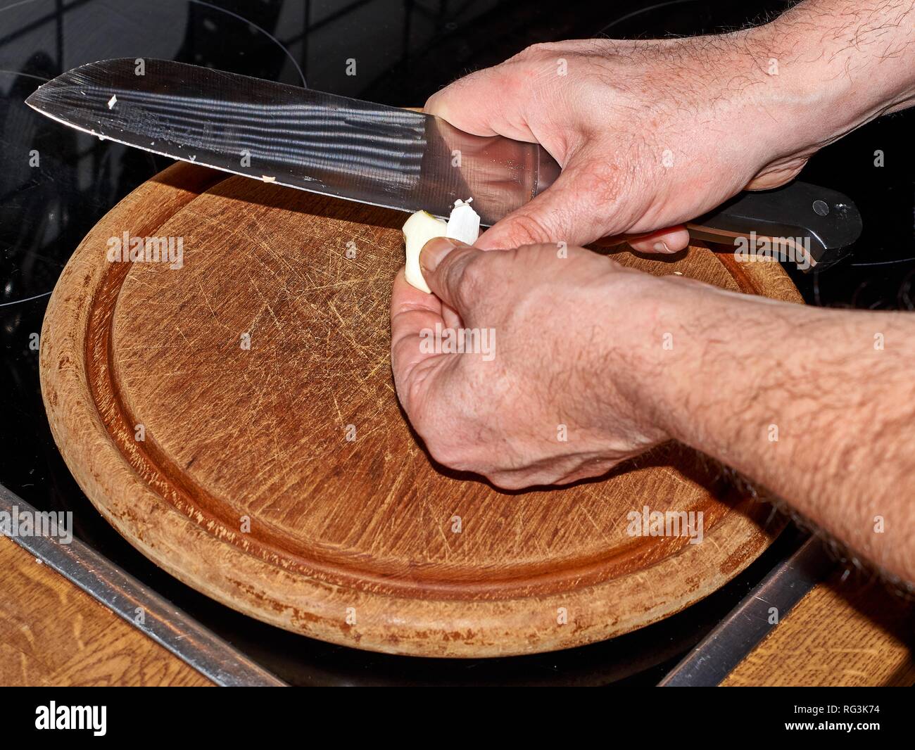 Chef slicing garlic Allium sativum on the cutting board with a knife ...