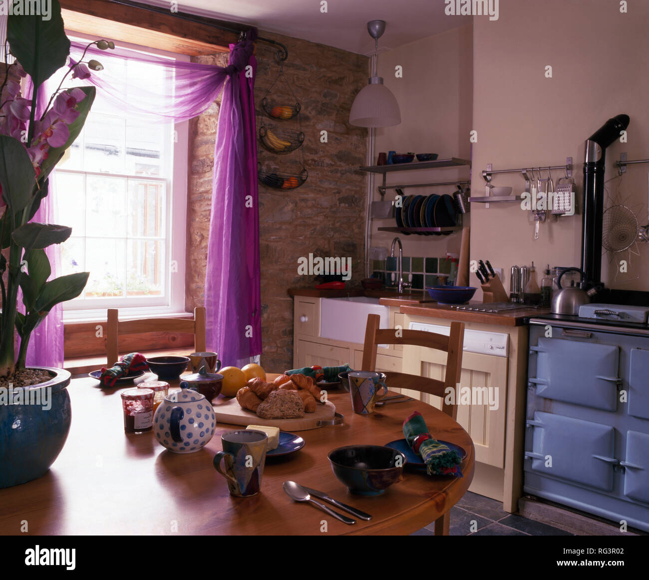 Table set for breakfast in economy style kitchen with blue Aga Stock ...