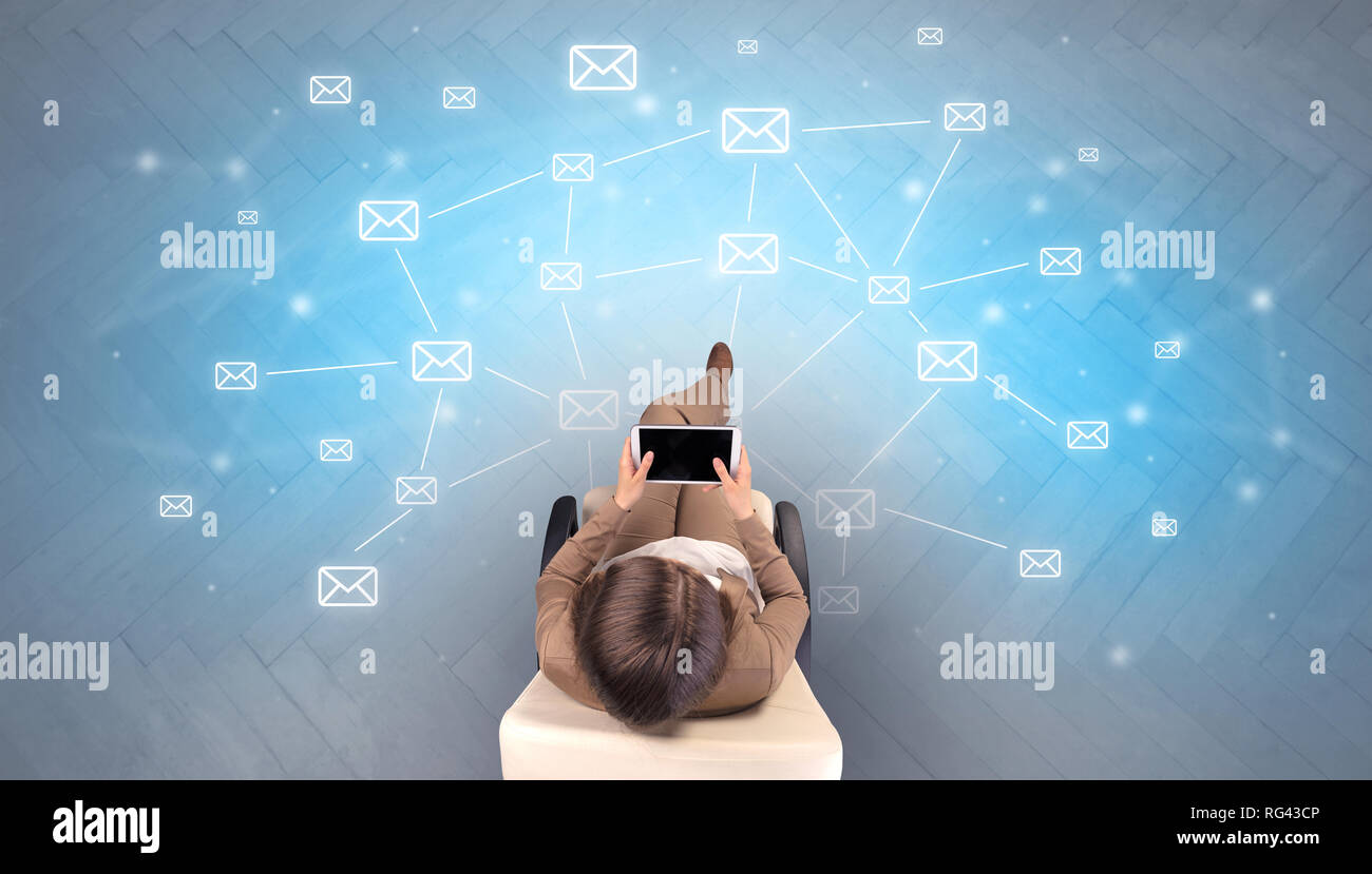Mail symbols with woman using device in a beige chair Stock Photo - Alamy