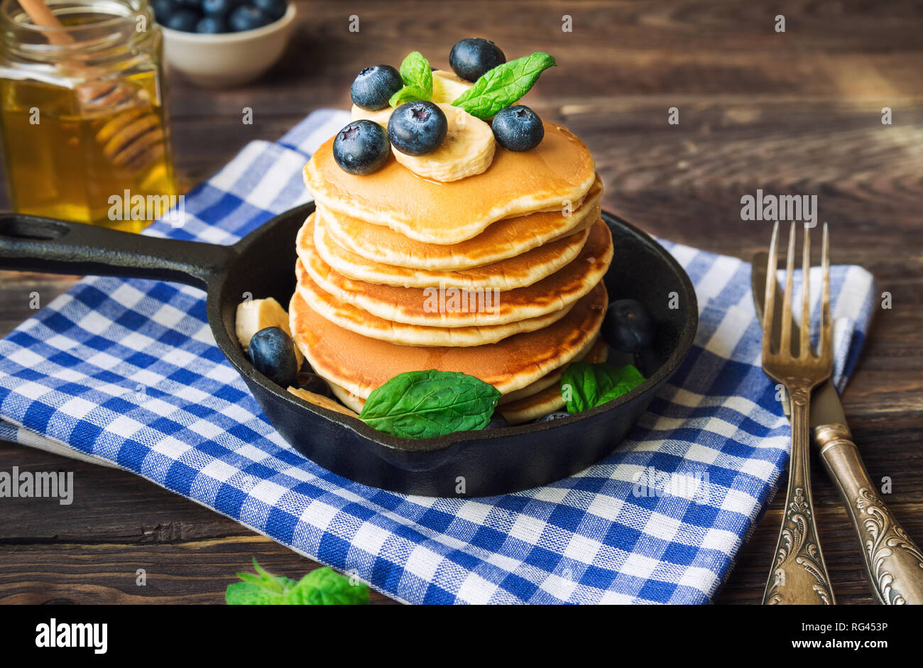 Stack of homemade pancakes in iron skillet with blueberries, banana and ...