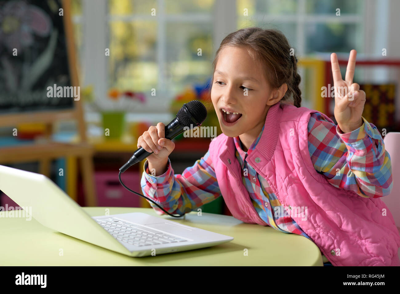 little girl using modern laptop and singing karaoke Stock Photo - Alamy