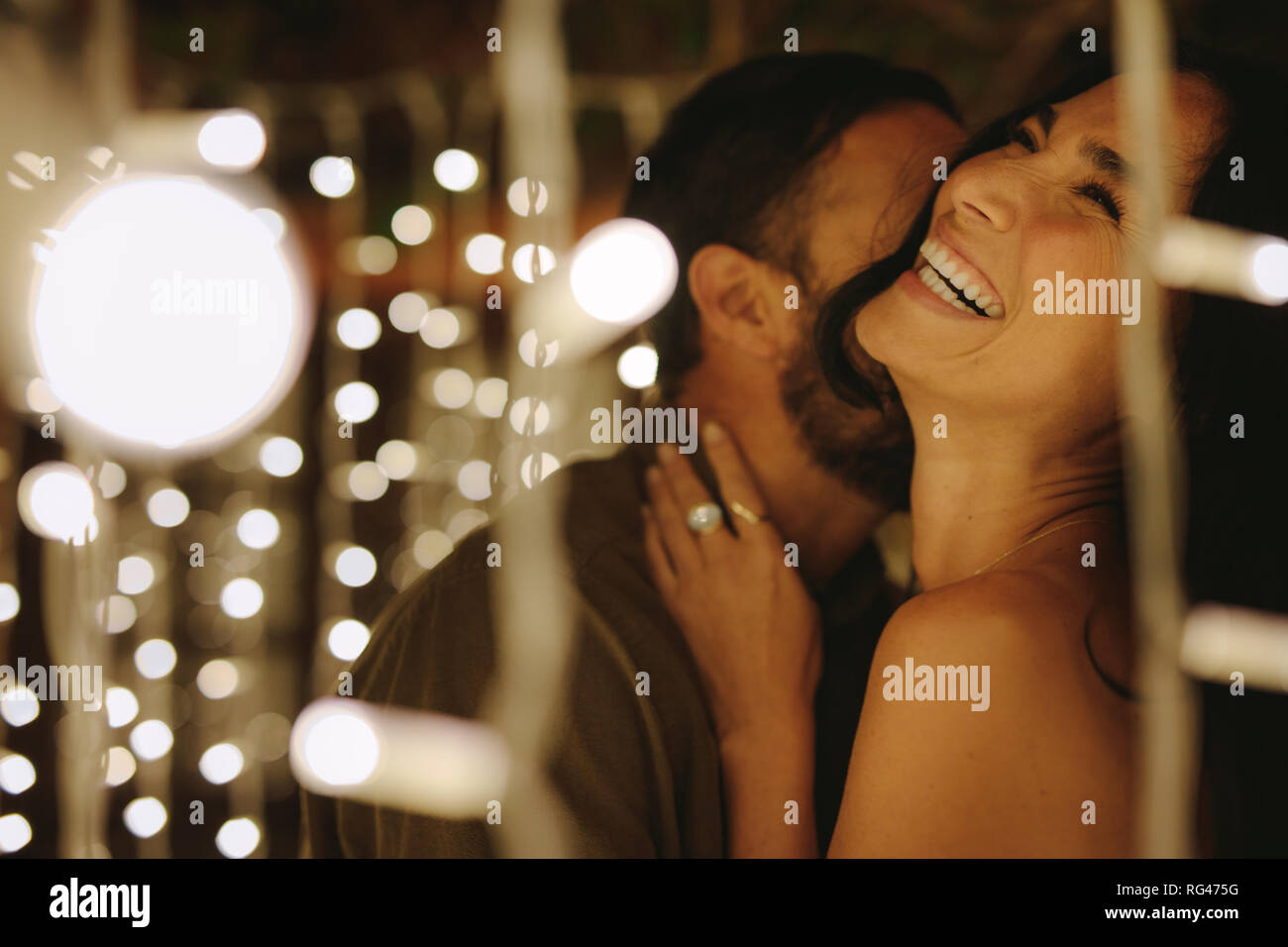 Happy young couple embracing with lights around at party. Young man and ...