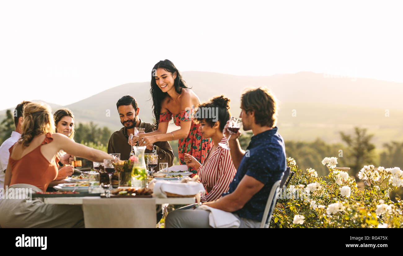 Woman serving food to friends at dinner party. Group of young people ...