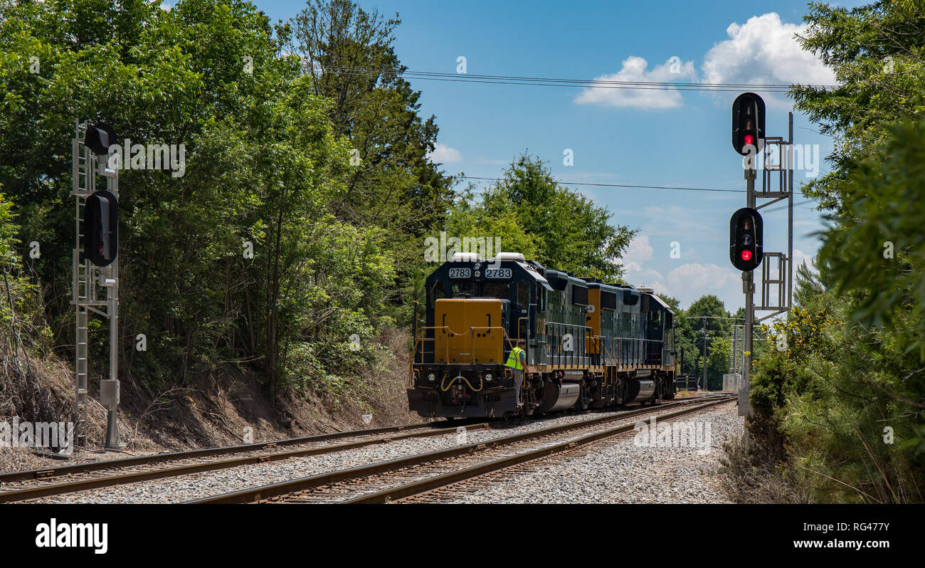 A long view of two railroad cars with flashing signals and an engineer ...