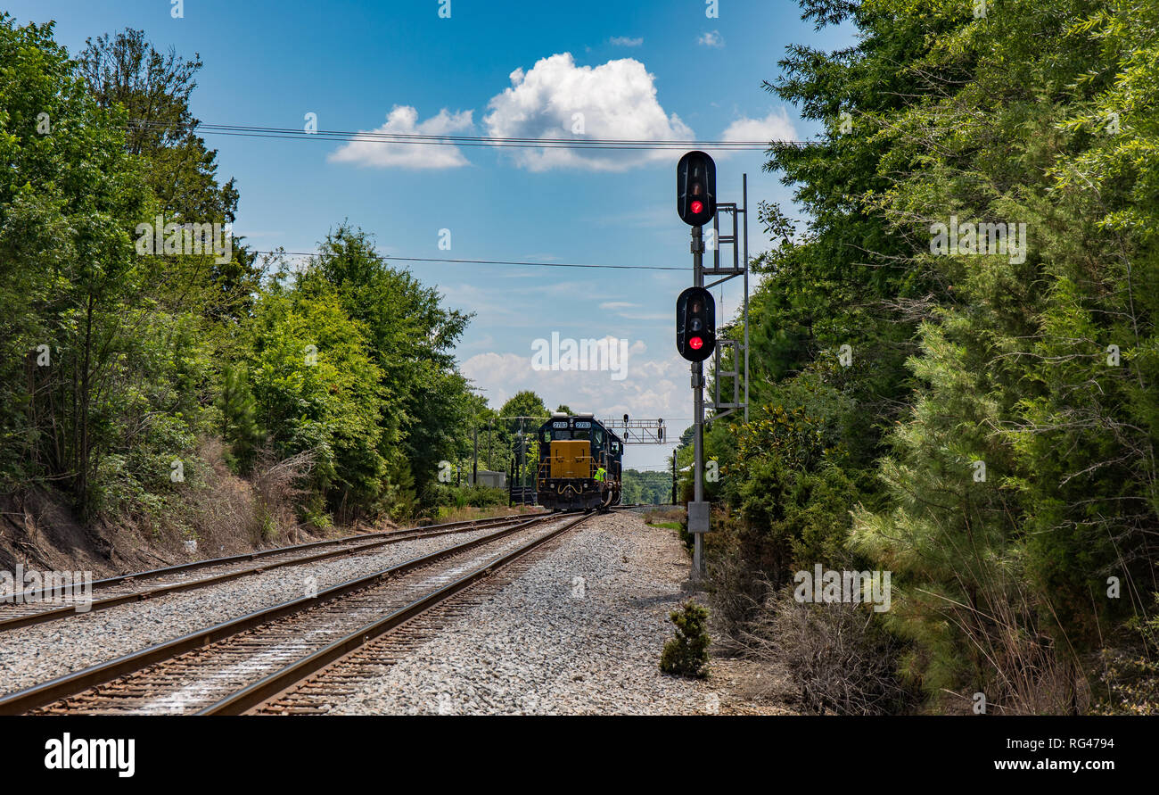 A long view of two railroad cars with flashing signals and an engineer ...