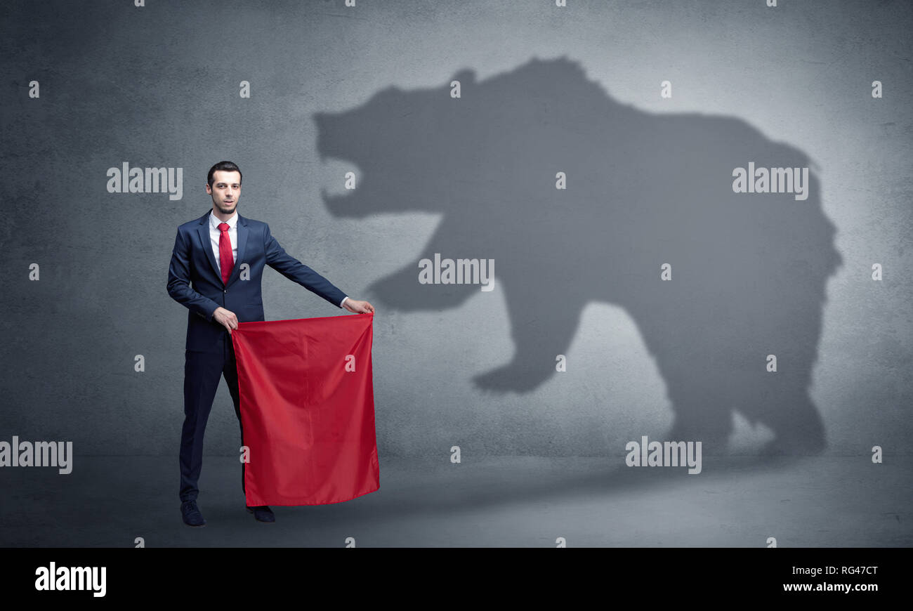 Businessman standing with red cloth in his hand and big bear shadow on ...