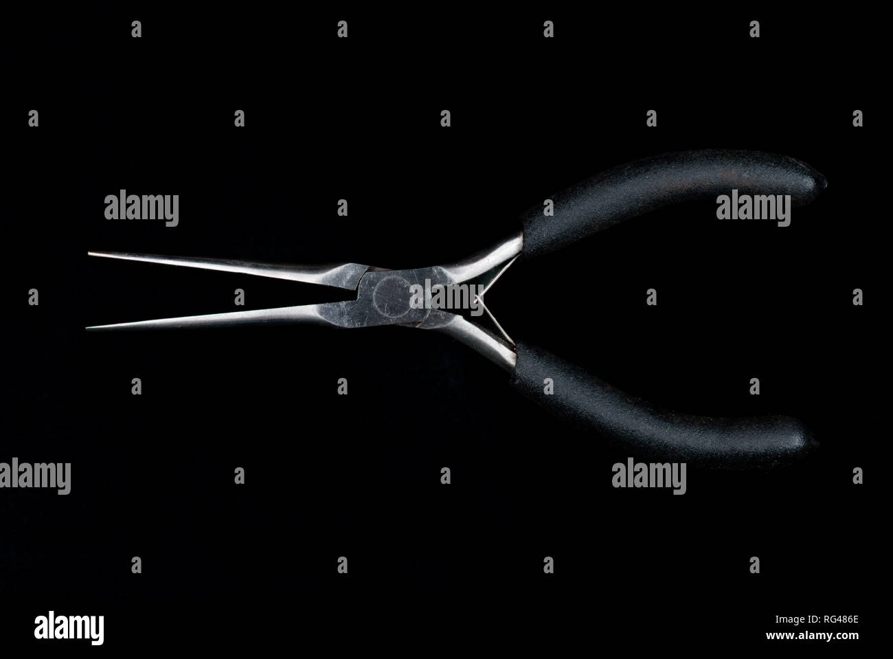long pointed narrow pliers on a black background Stock Photo - Alamy
