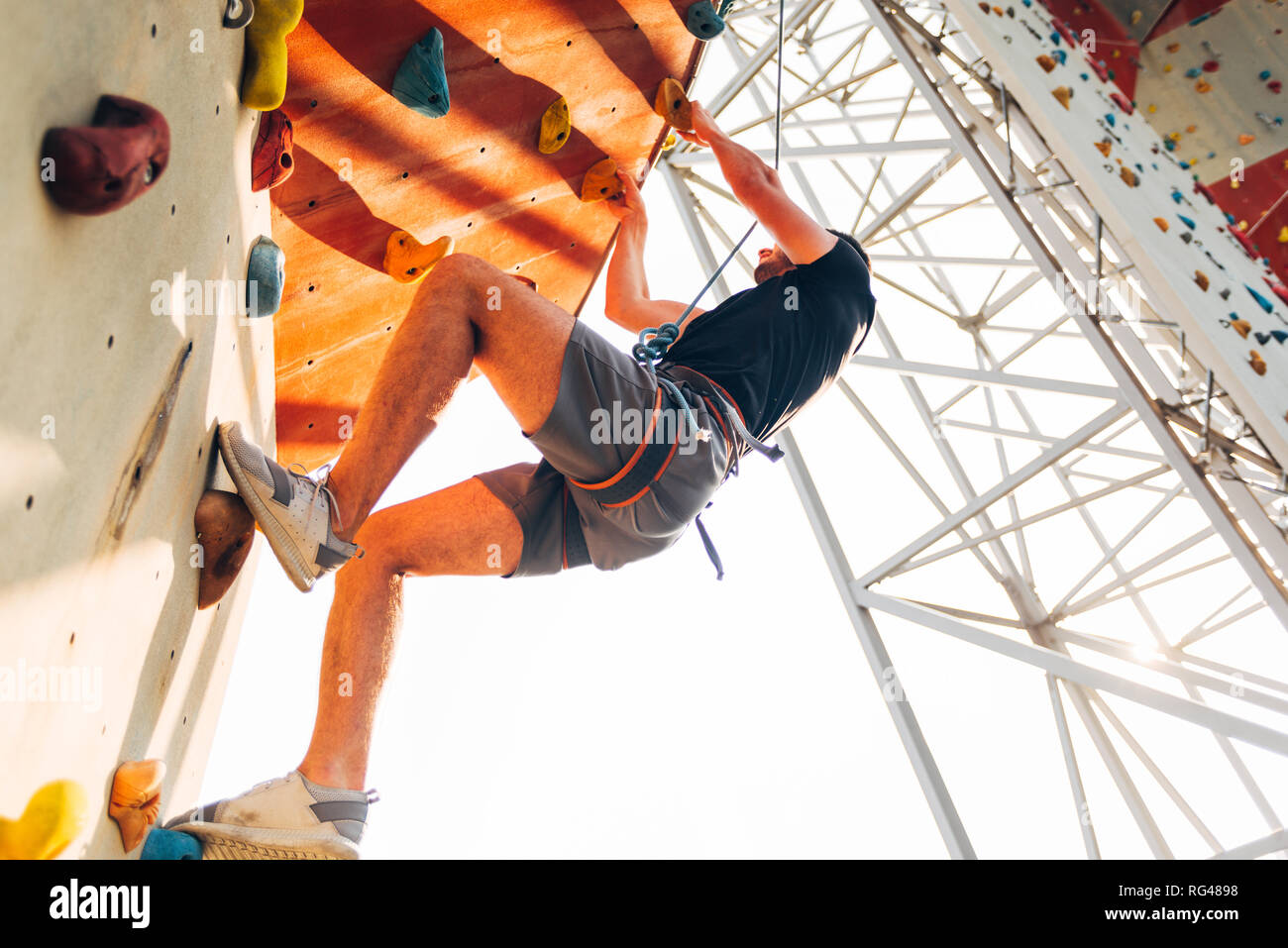 Young climber guy climbing on practical rock in climbing center ...