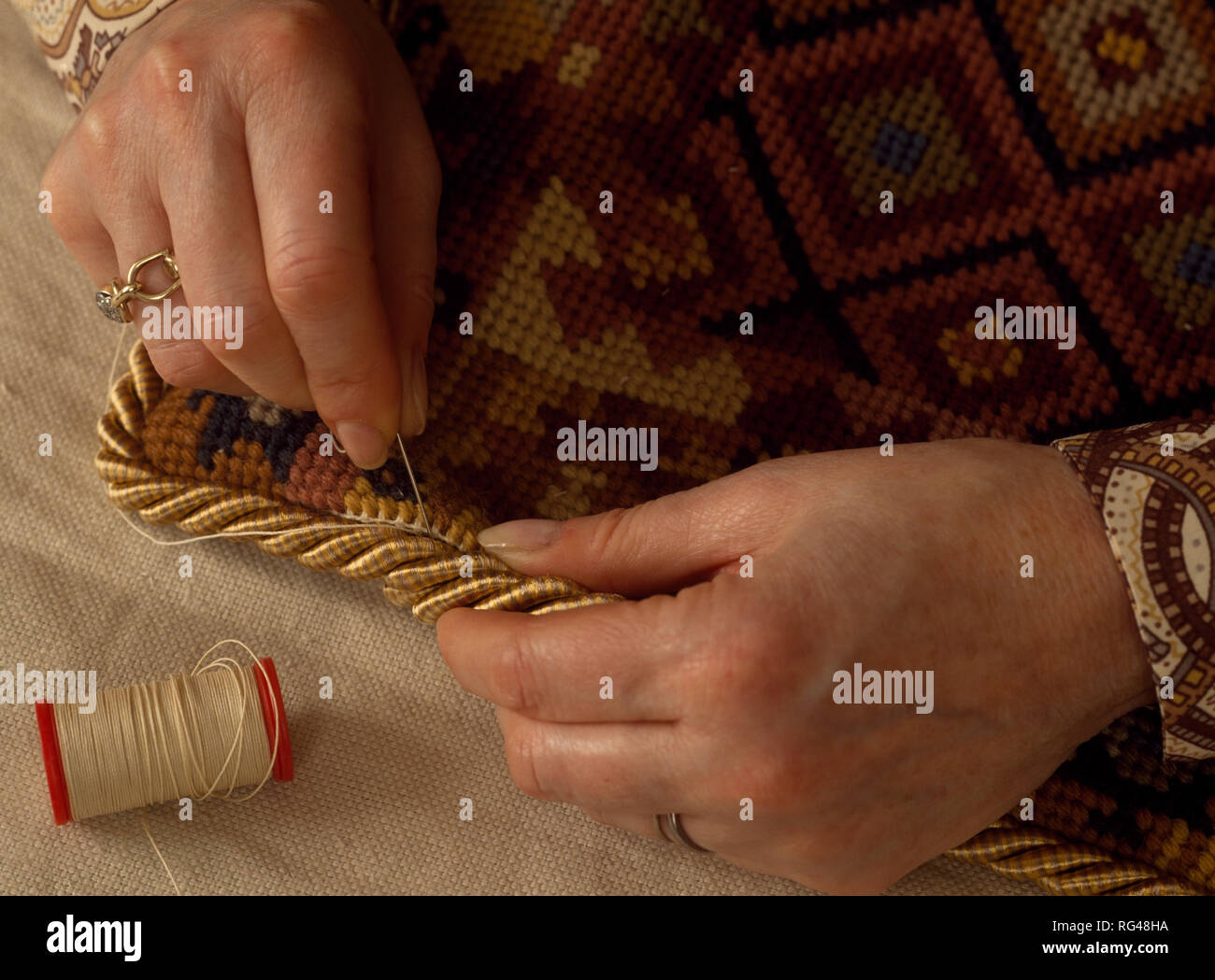 Hands sewing silk cord onto tapestry Stock Photo - Alamy