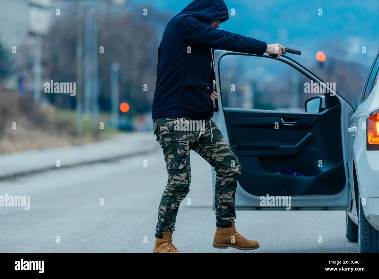 The car thief is pulling the car owner out of his car and trying to get ...