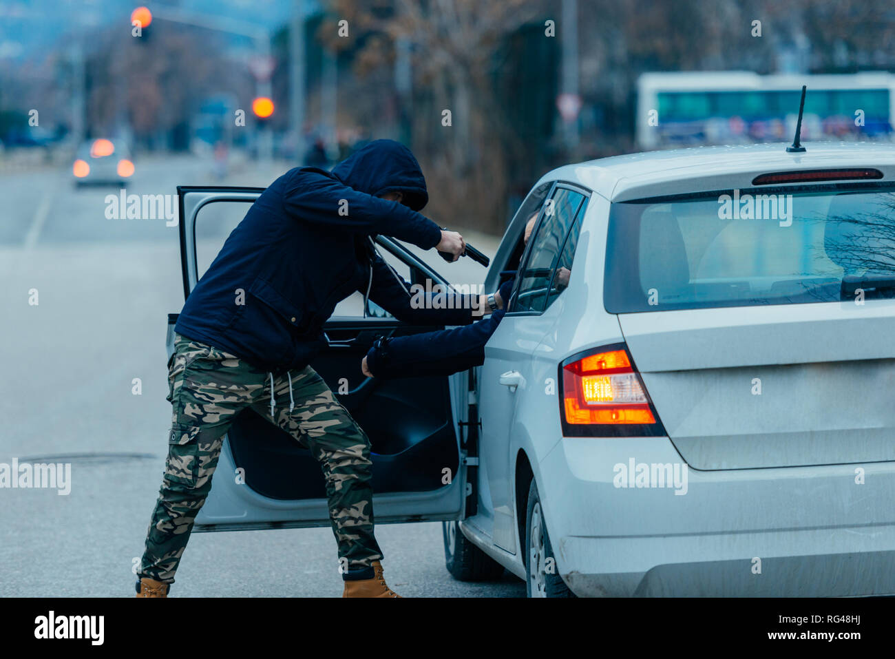 The car thief is pulling the car owner out of his car and trying to get ...